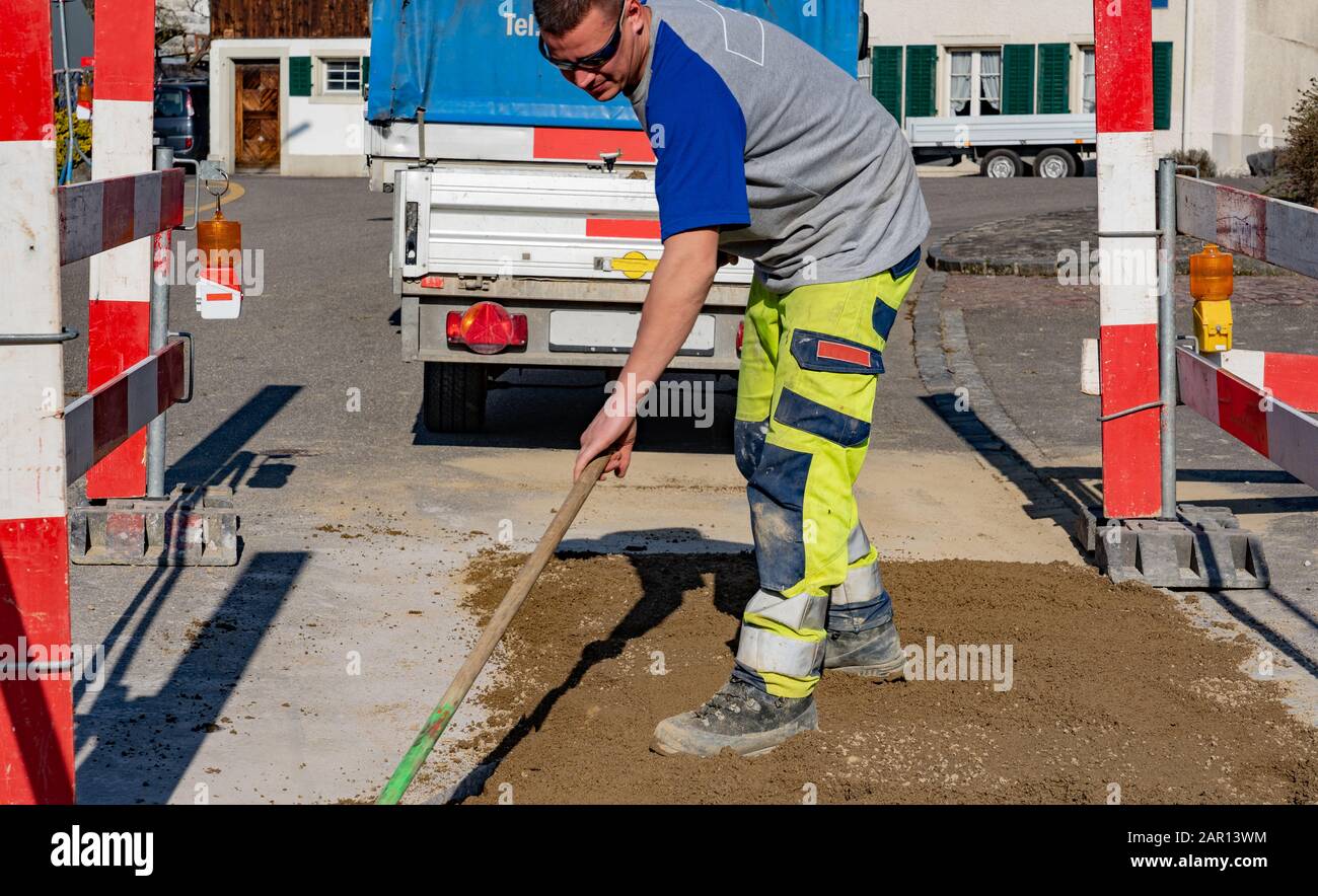 Construction worker with sunglasses and broomstick scrubbing sand in ...