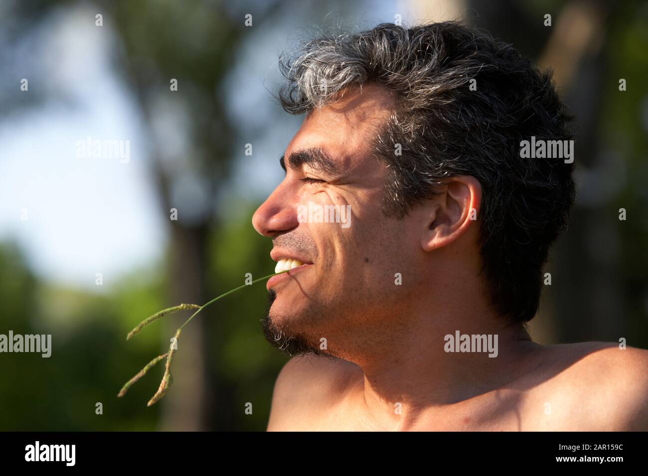 30s hispanic man eating grass and smiling in park buenos aires ...