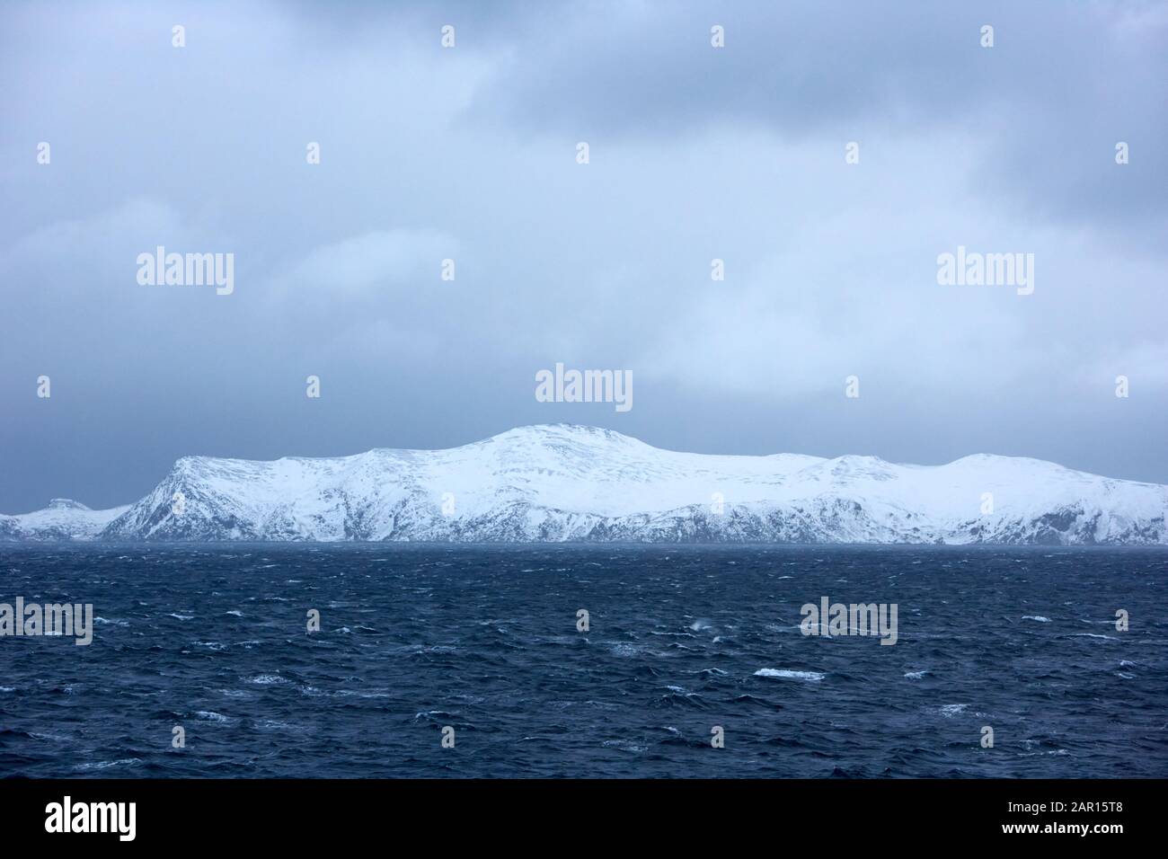 snow covered coastline in rough seas on Norwegian Arctic coast Stock ...