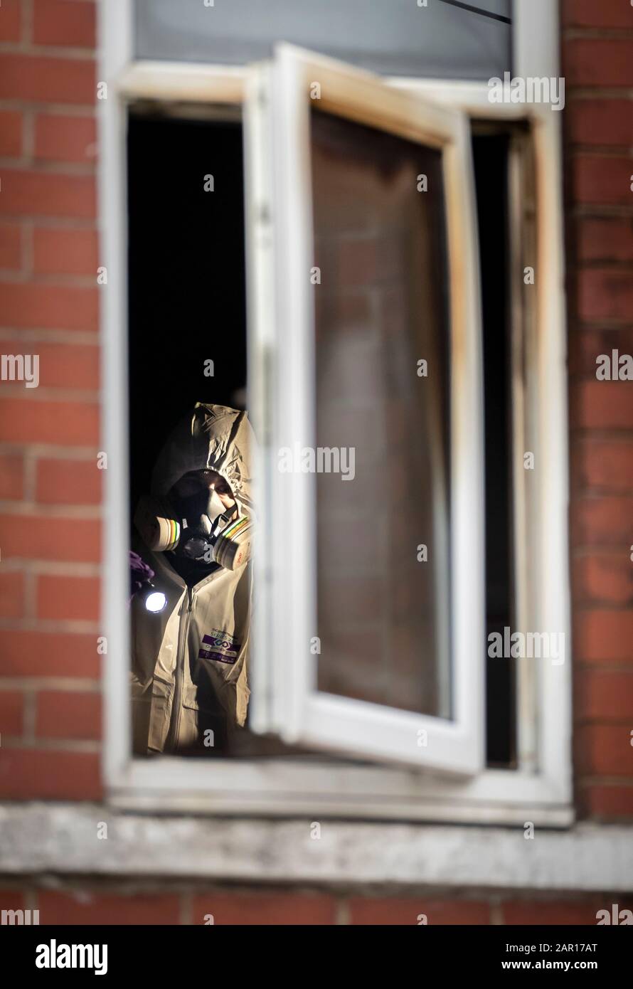 Forensics officers is seen through a damaged open window at the scene ...