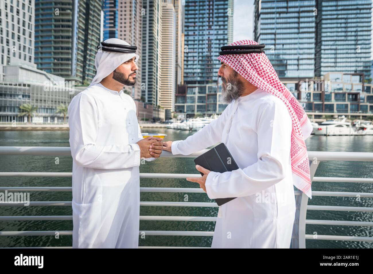 Two businessmen with traditional emirates clothes meeting in Dubai ...