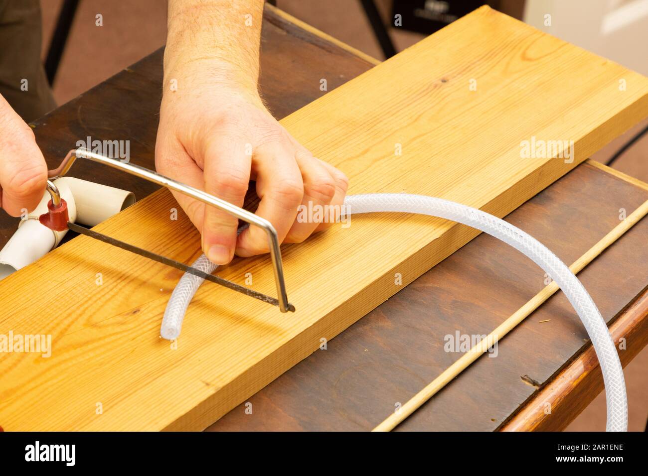 A junior hack saw being used to cut a small piece of plastic tubing ...