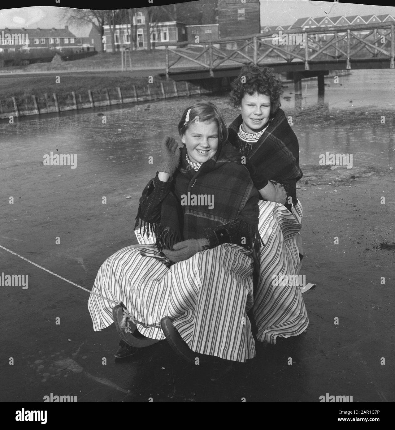 Girls in traditional costume on the ice in Volendam Two girls sitting ...