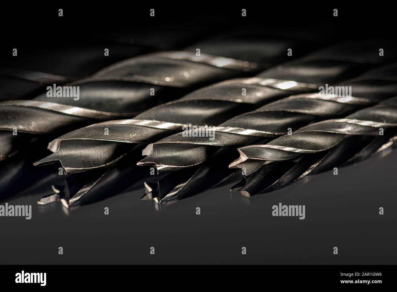 Extreme close-up of black and grey drill tips on a dark background with ...