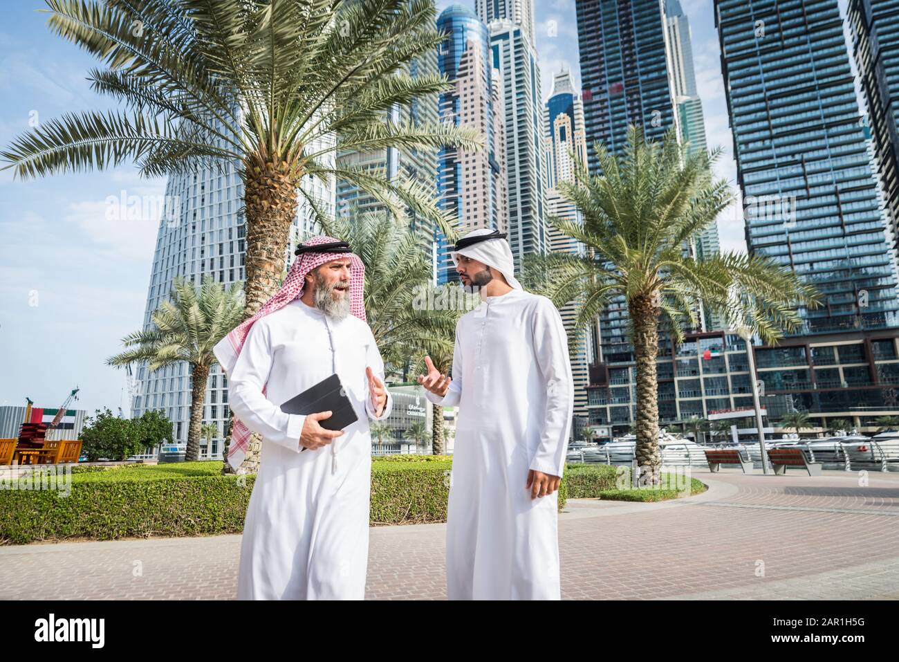Two businessmen with traditional emirates clothes meeting in Dubai ...