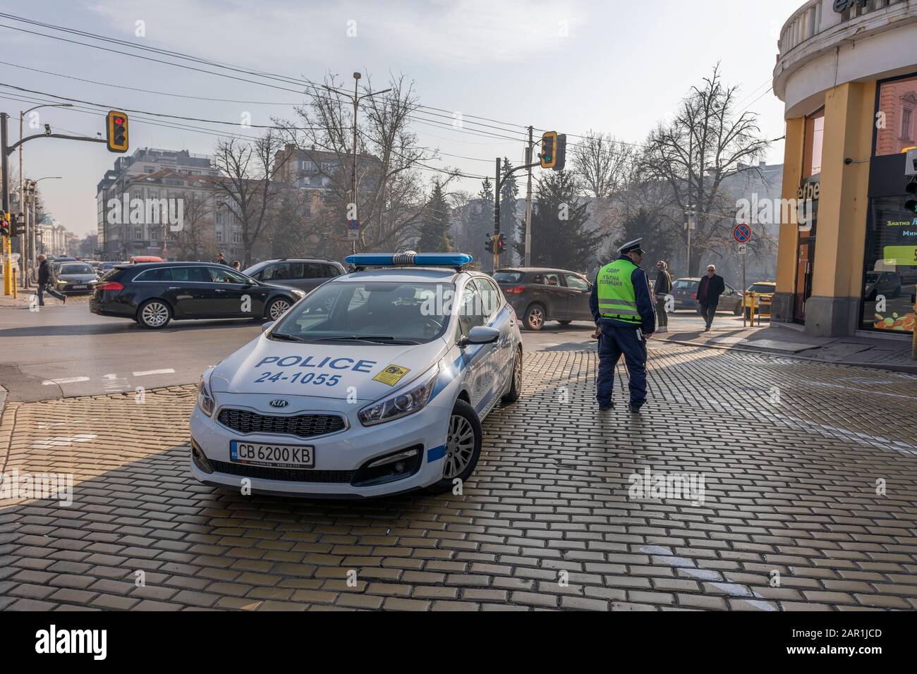 A police officer standing near his car with the light on. Police stand ...