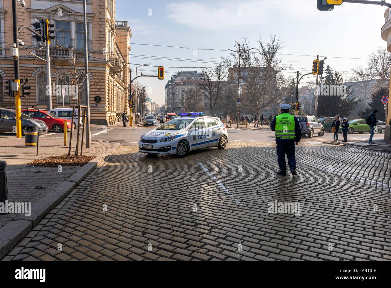 A police officer standing near his car with the light on. Police stand ...