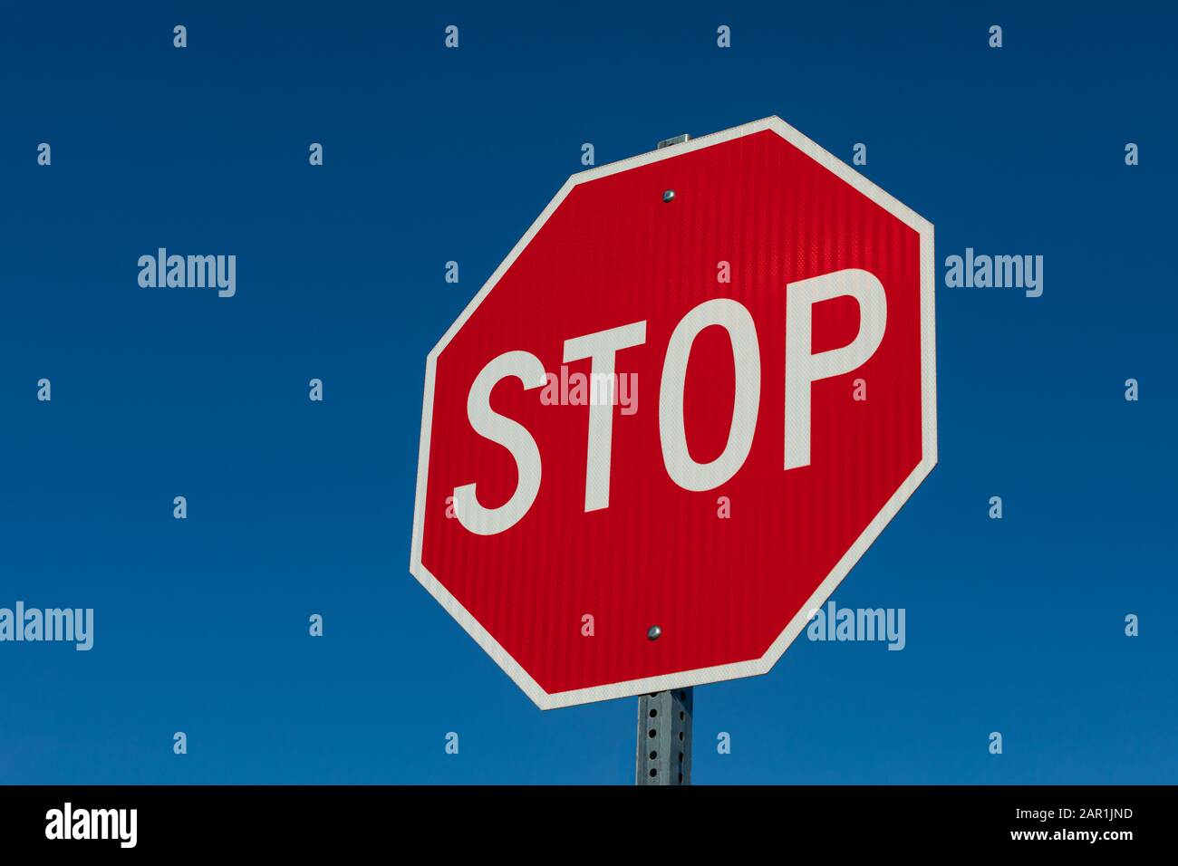 Closeup angled view of reflective stop sign isolated on deep blue sky ...