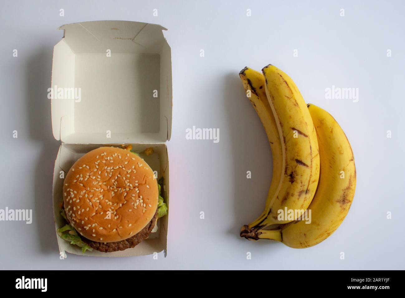 Banana put next to a burger and a vacant box on a white surface Stock ...