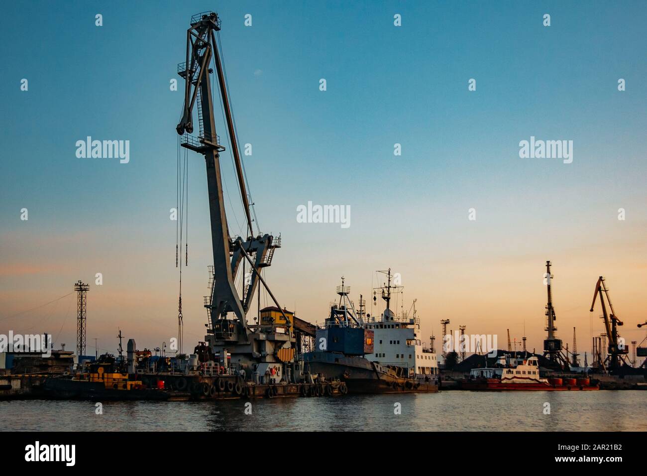 Harbor cargo cranes on evening sky background Stock Photo - Alamy
