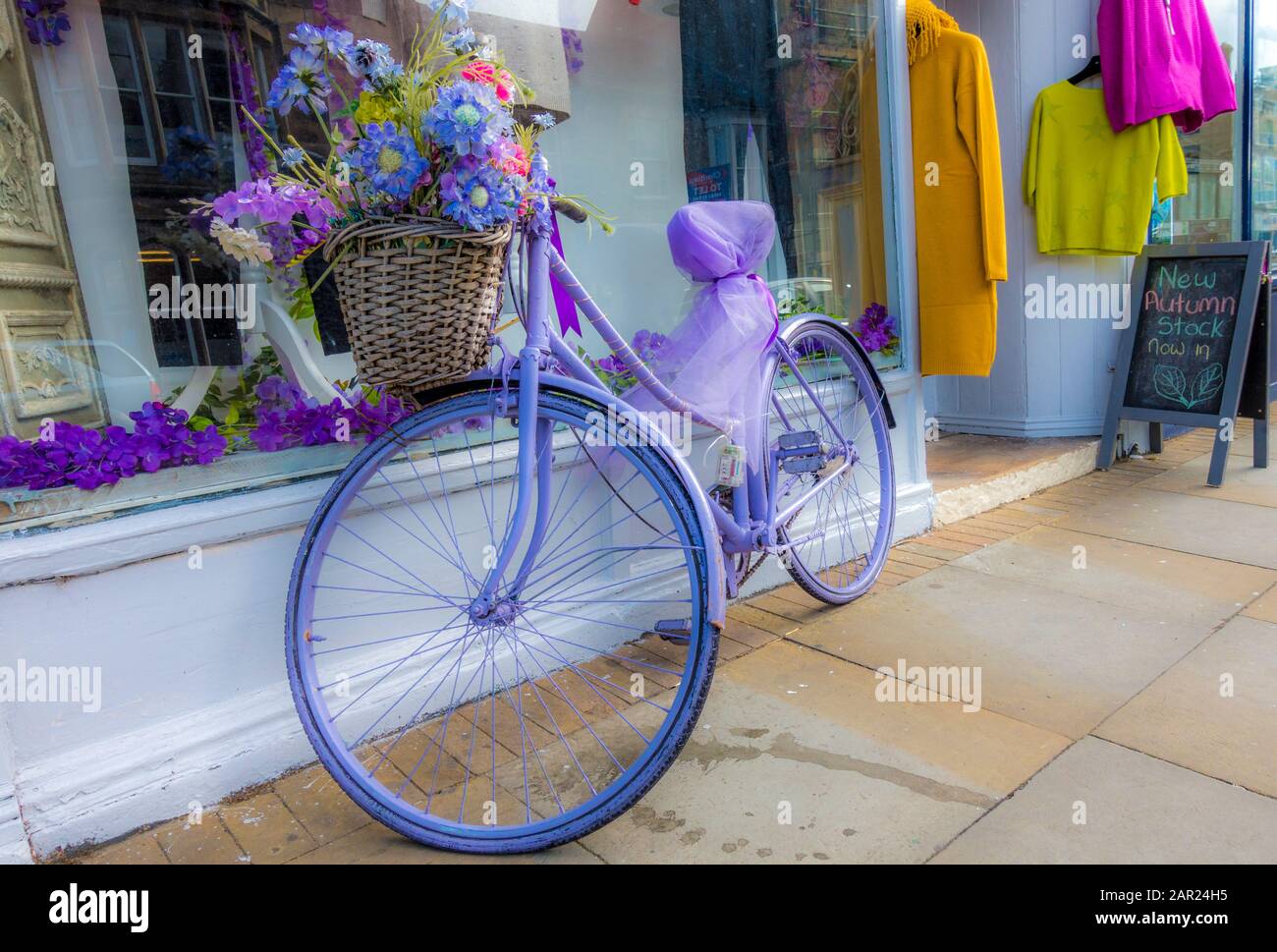 A lilac painted bicycle, colourful clothing and flowers, artfully ...