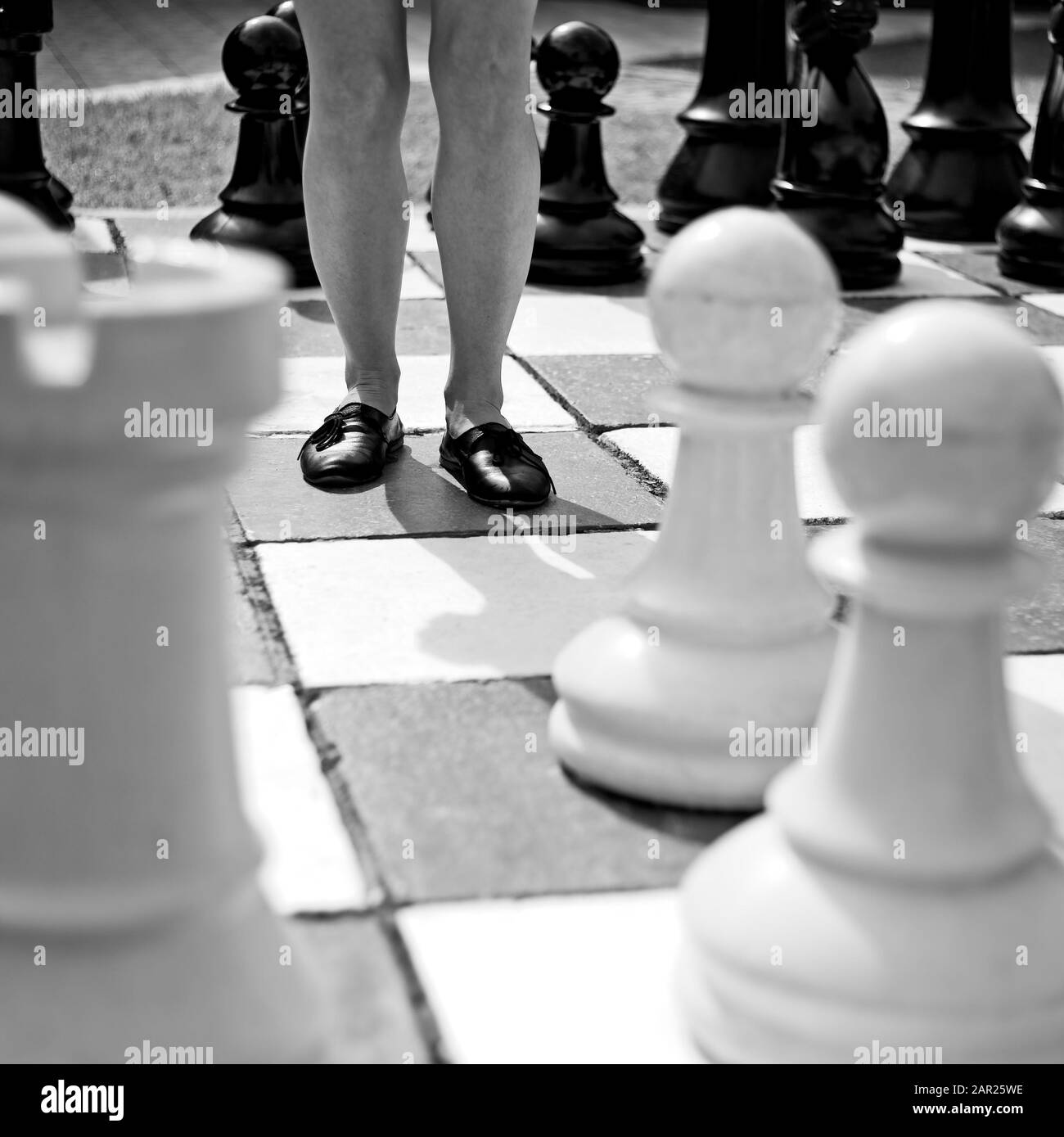 Grey scale shot of a female standing in the middle of a big chess board ...