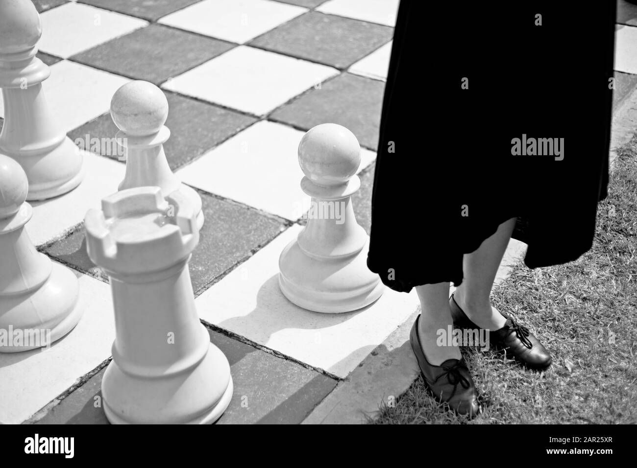 Grey scale shot of a female wearing a black dress standing by a big ...