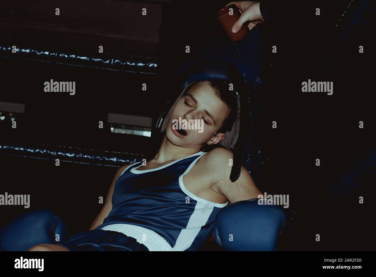 teenager boxer lies in the corner of the ring after a knockout and the ...