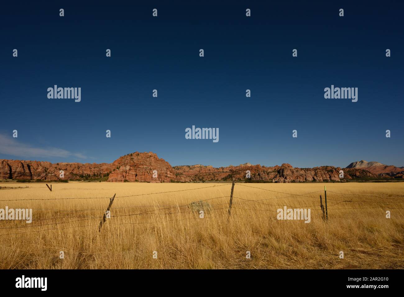 Mangled Old Barbed Wire Fence and Grassy Field with deep blue sky Stock ...