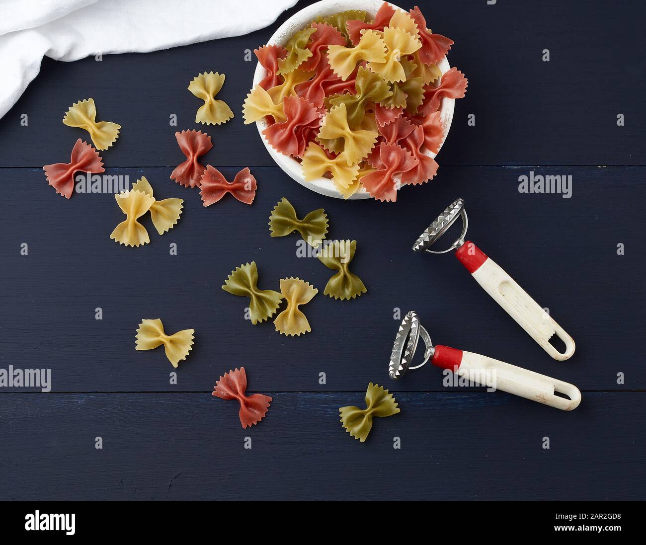 raw pasta in the form of bows in a wooden round plate and white textile ...