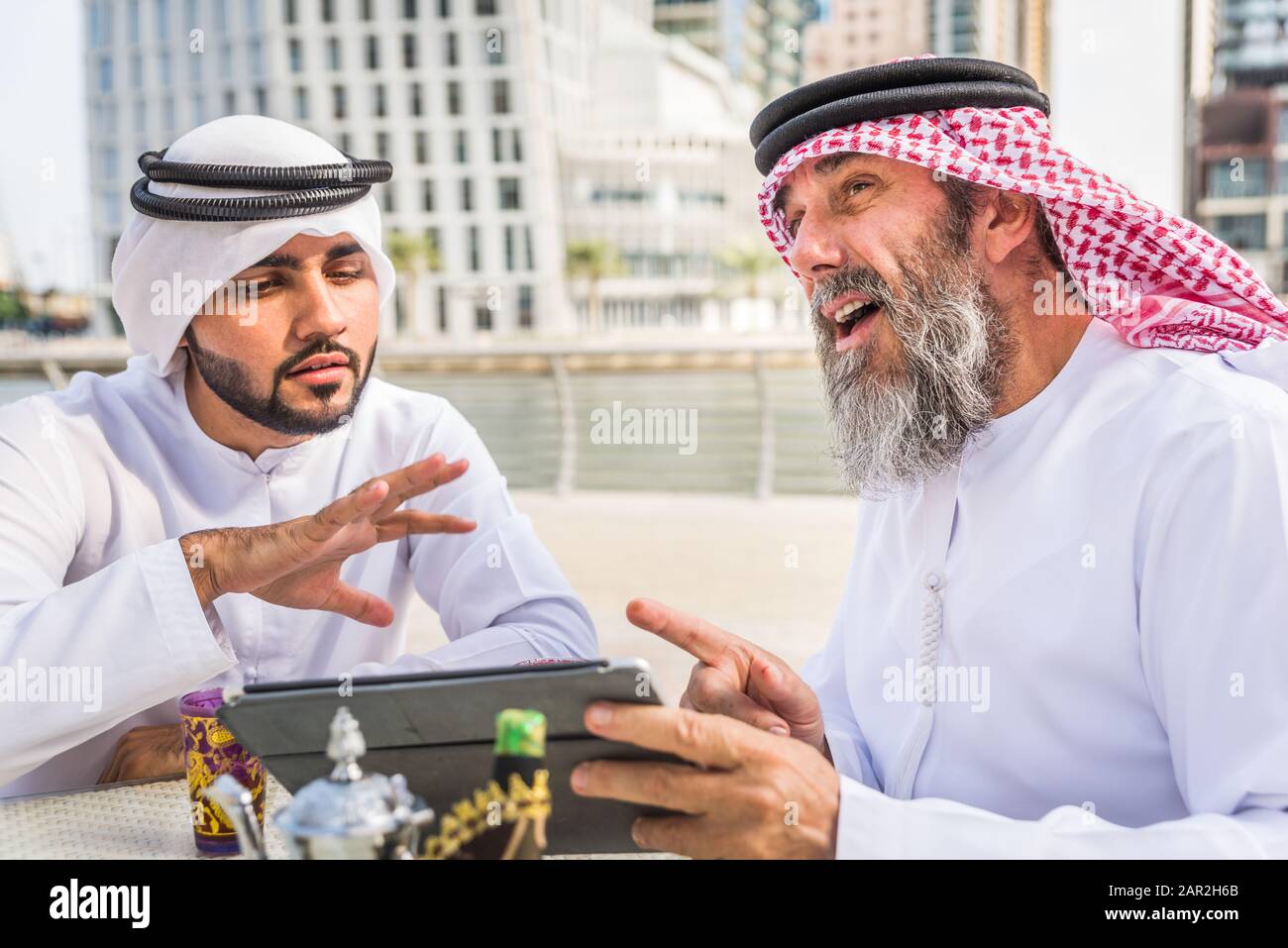 Two businessmen with traditional emirates clothes meeting in Dubai ...