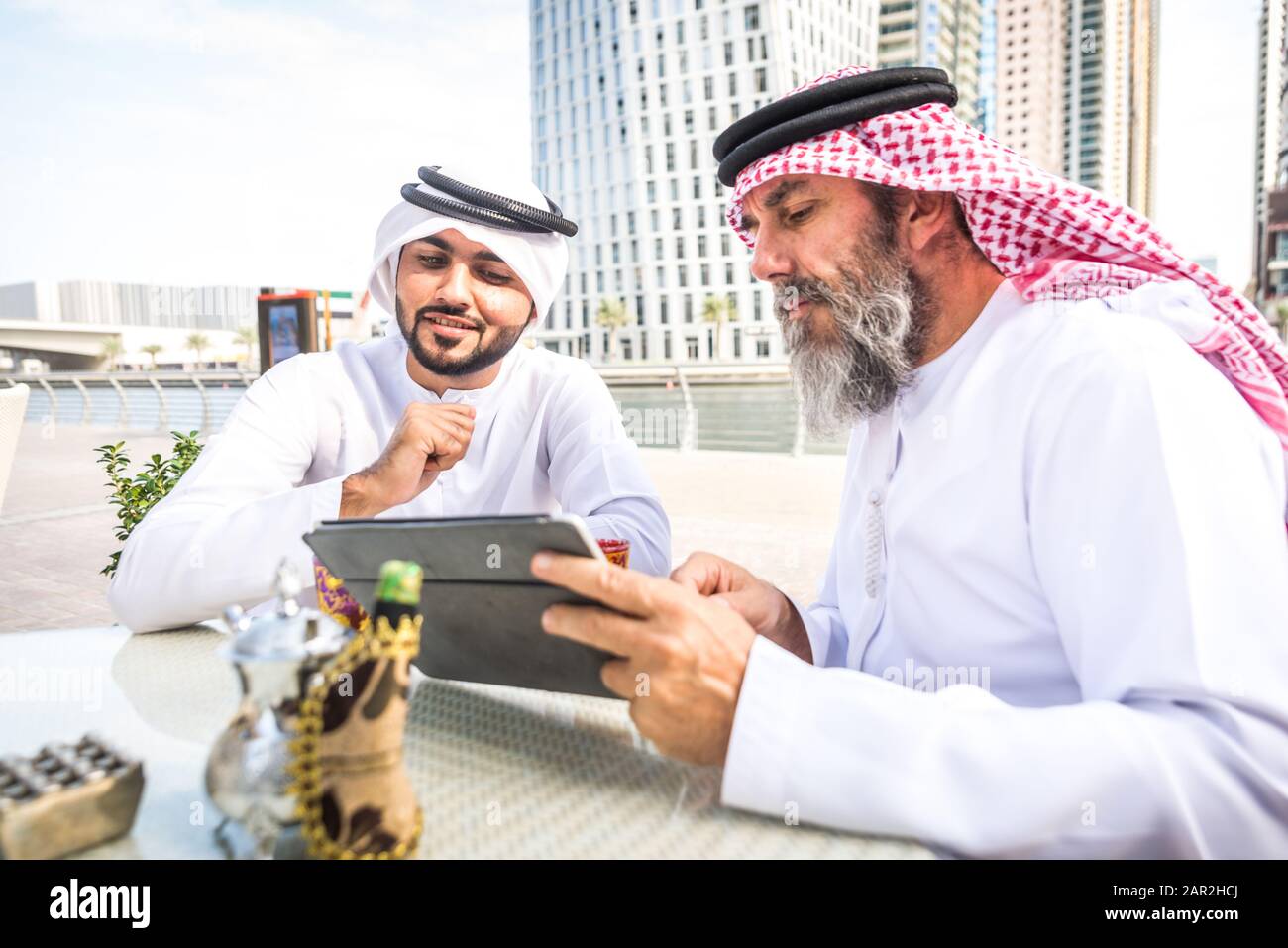 Two businessmen with traditional emirates clothes meeting in Dubai ...