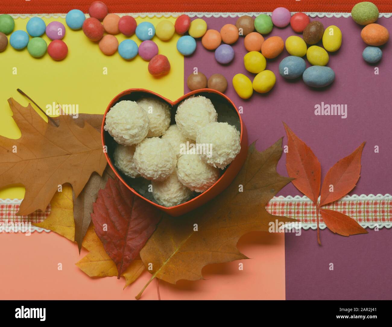 Coconut candy in a red heart on colorful background. Sweets near autumn ...