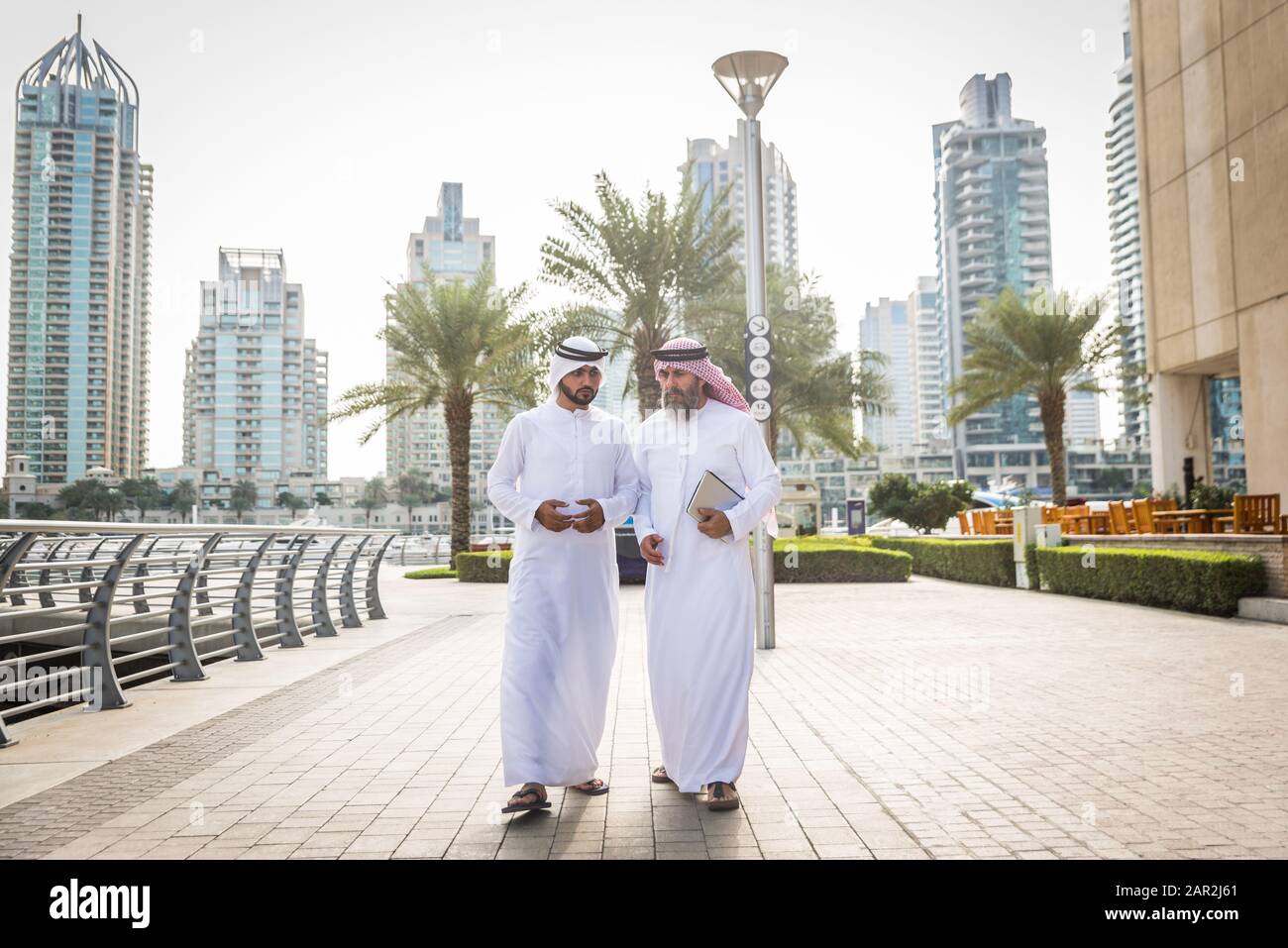 Two businessmen with traditional emirates clothes meeting in Dubai ...
