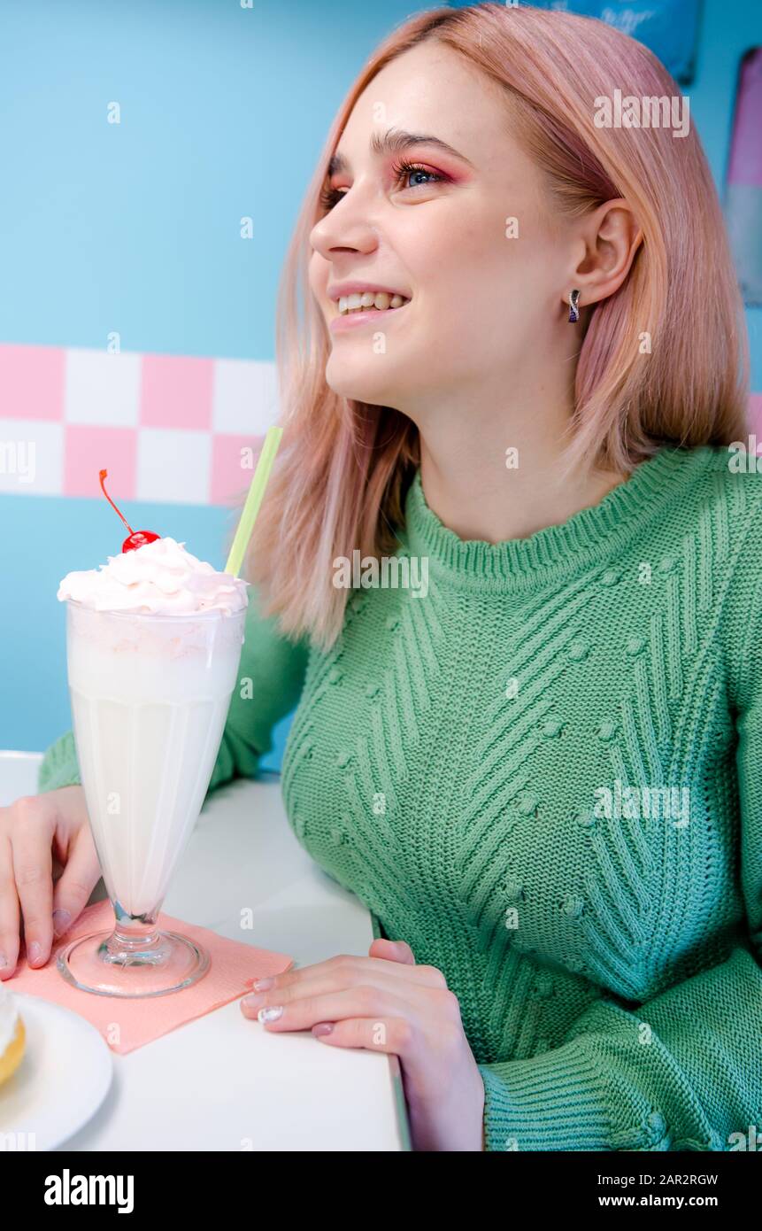 Portrait of a pretty girl in cafe. Pretty blonde girl with a milkshake ...