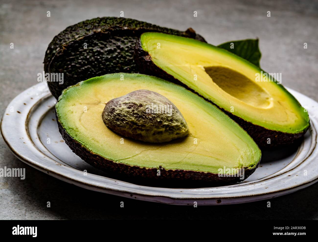 New harvest of fresh ripe hass avocado close cut in half with seed ...