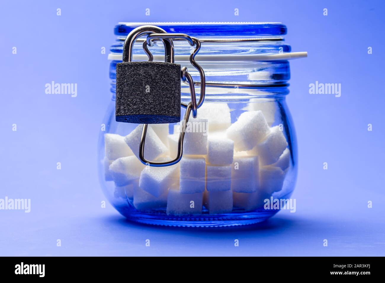 Cubes of white sugar in a transparent glass jar with a lid closed on a ...