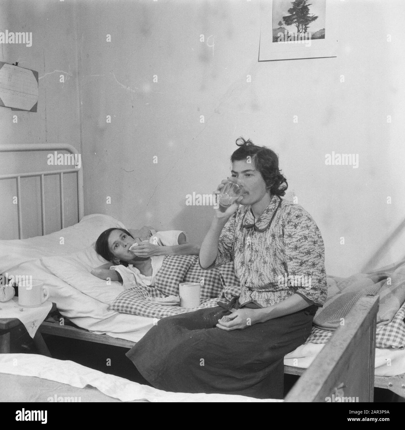 Repatriation camp Bergen-Belsen [Two women drink and eat. One of them ...