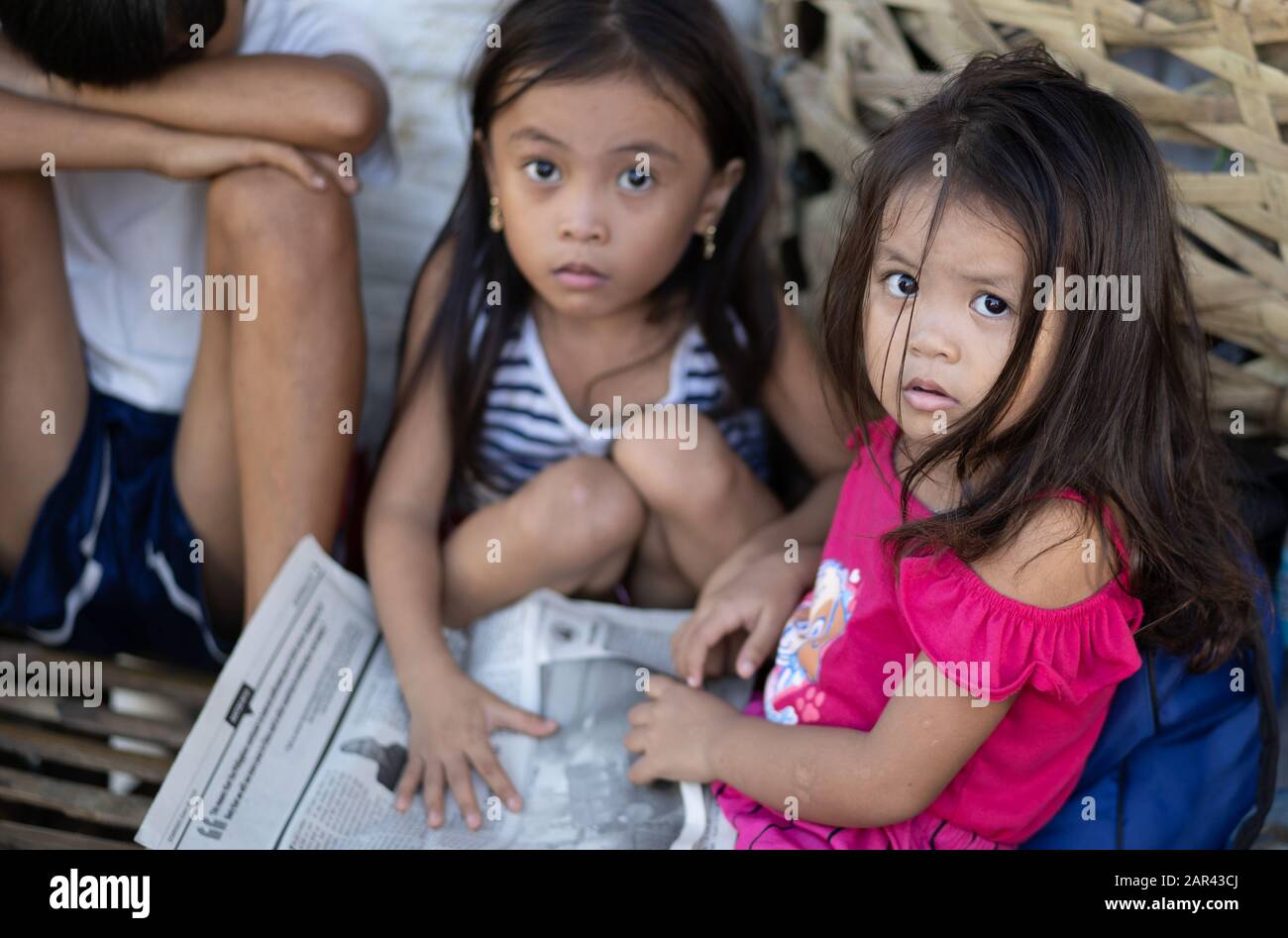 Young children play with a newspaper within a poor area of Cebu City ...