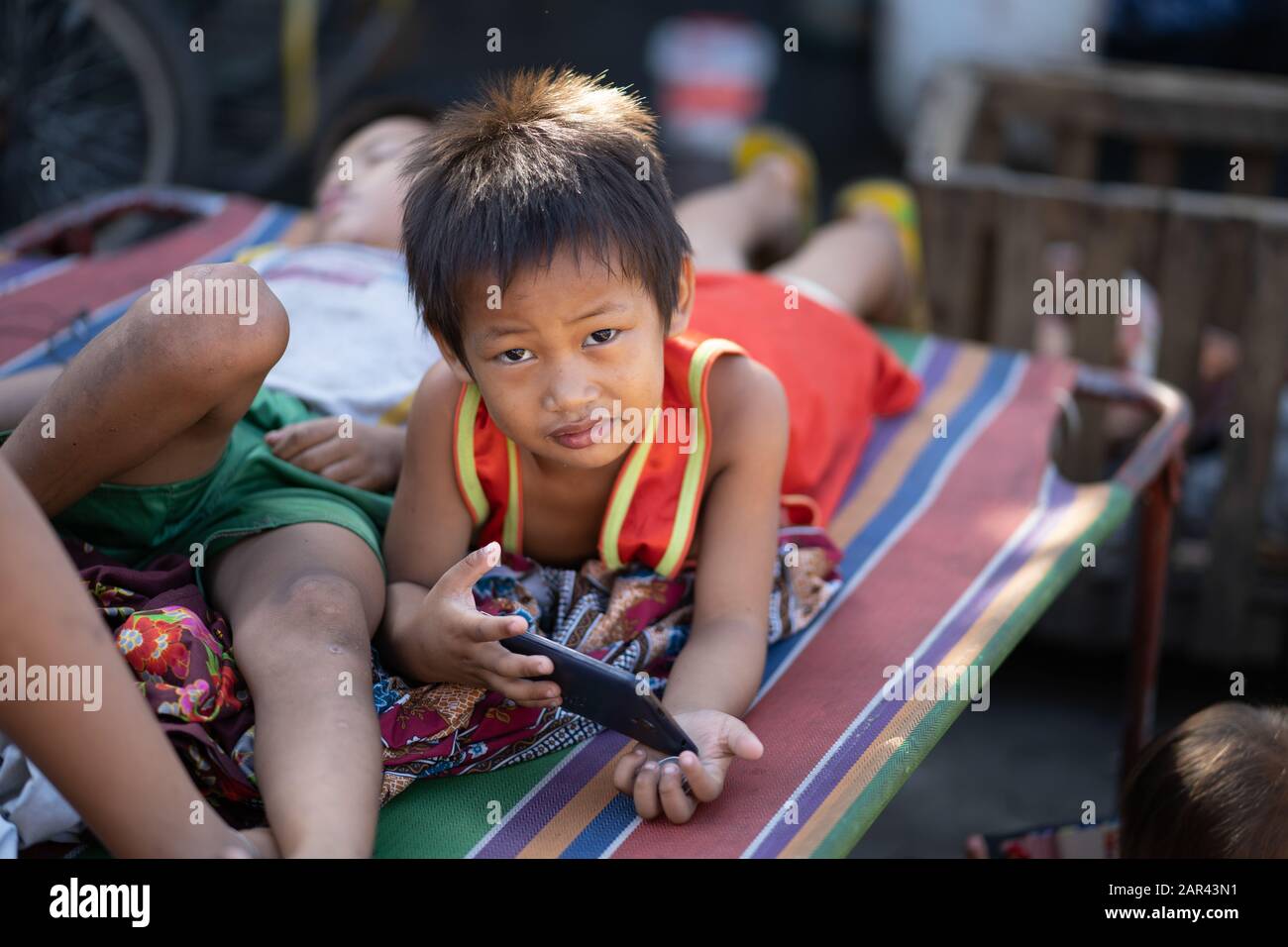 A young boy using a mobile phone alongside other children within a poor ...