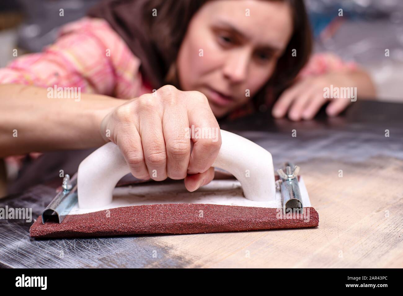 Female hand, with a carpentry holder for sandpaper, erases and polishes ...