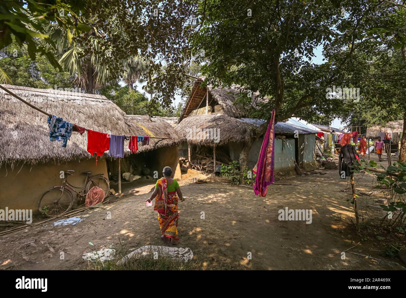 Rural Indian village scene with woman carrying bucket of water with ...