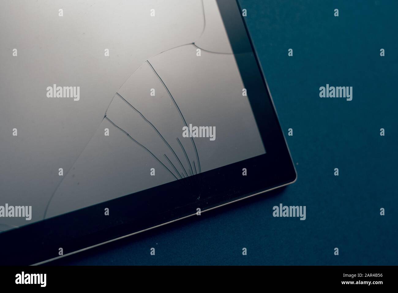 Modern tablet on a classic blue background with cracks. Broken screen ...