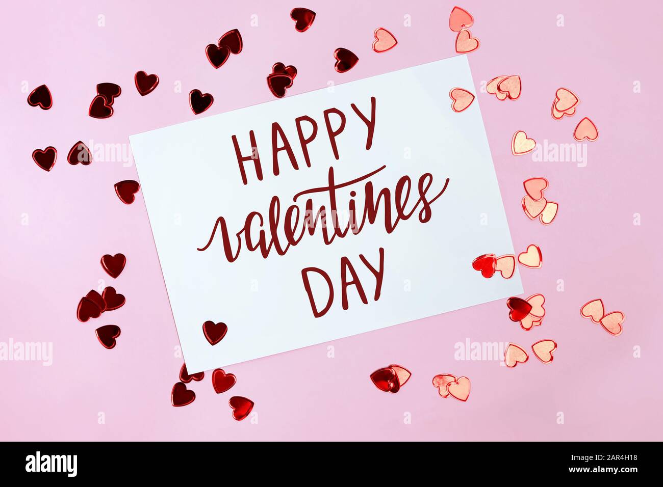 Valentines day greeting card and small red hearts over pink background ...