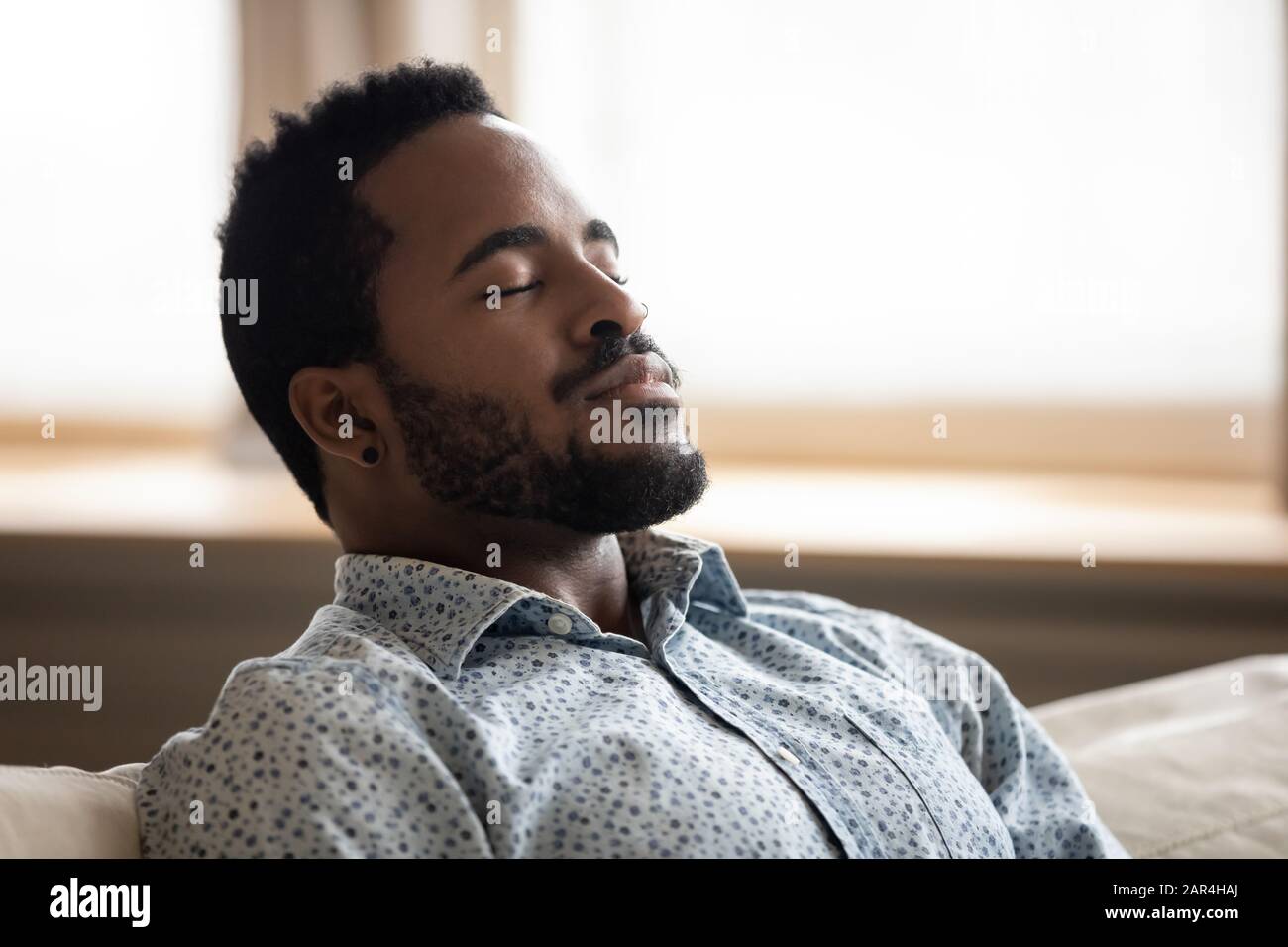 Tranquil young african man resting eyes closed breathing on couch Stock ...