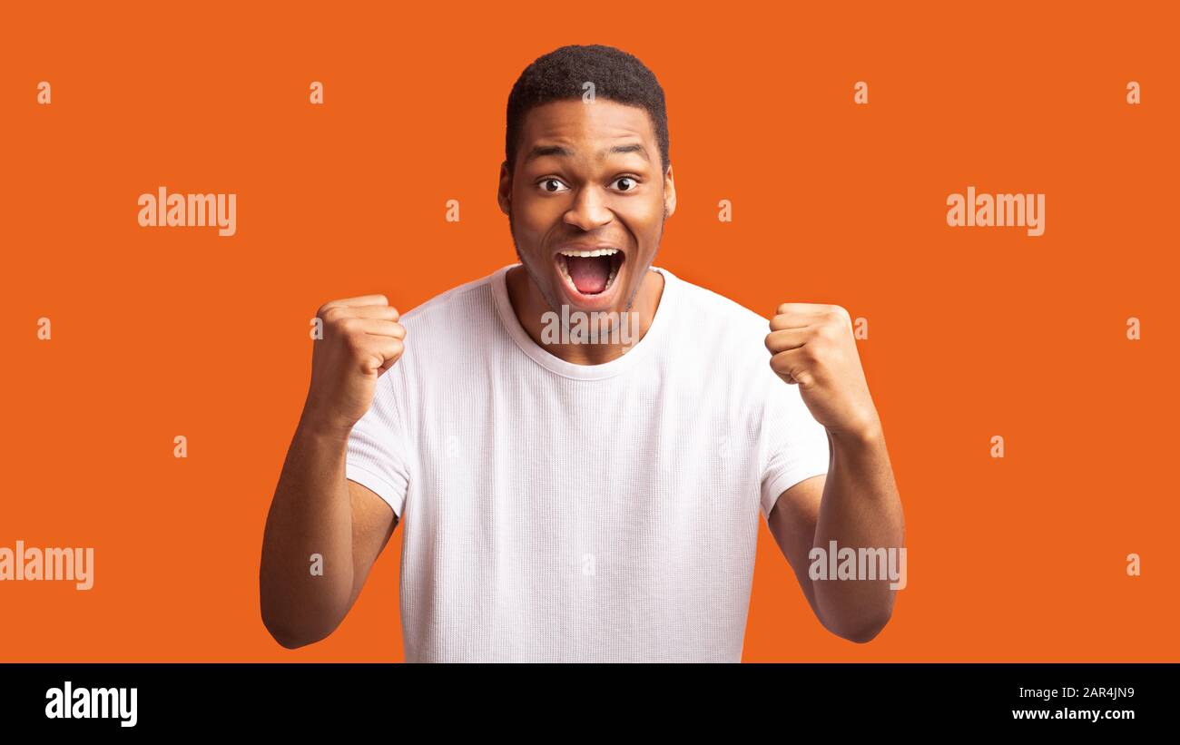 Afro man shouting over orange studio background Stock Photo - Alamy