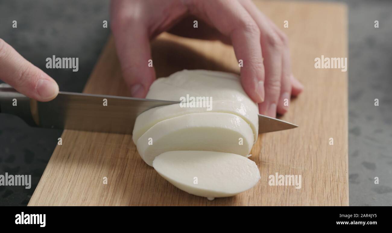 Closeup man slicing fresh mozzarella on oak board, wide photo Stock ...