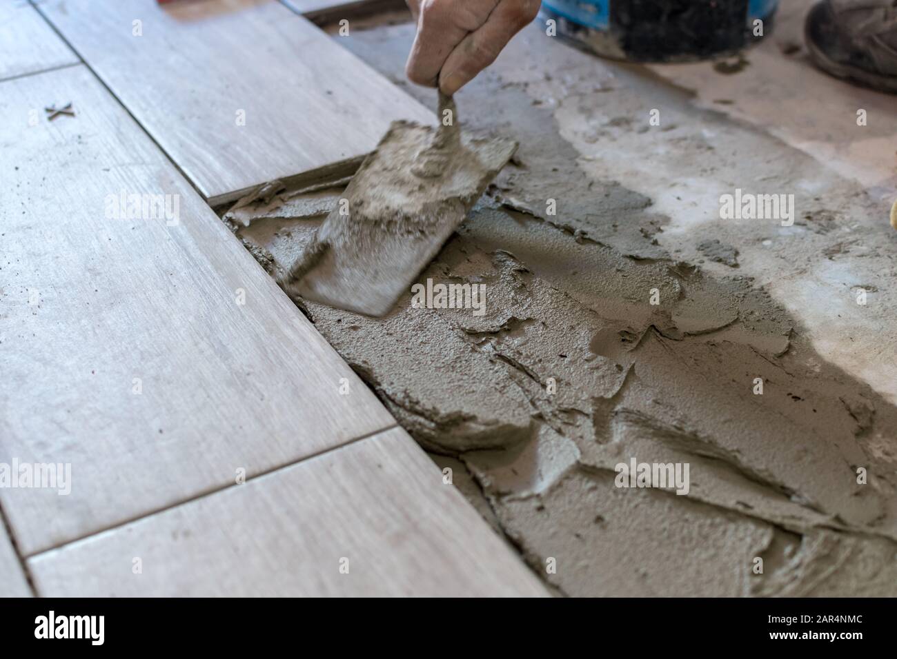 Man installing rectangular shaped floor tiles in kitchen. Applying ...