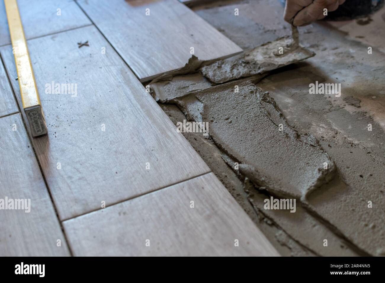Man installing rectangular shaped floor tiles in kitchen. Applying ...