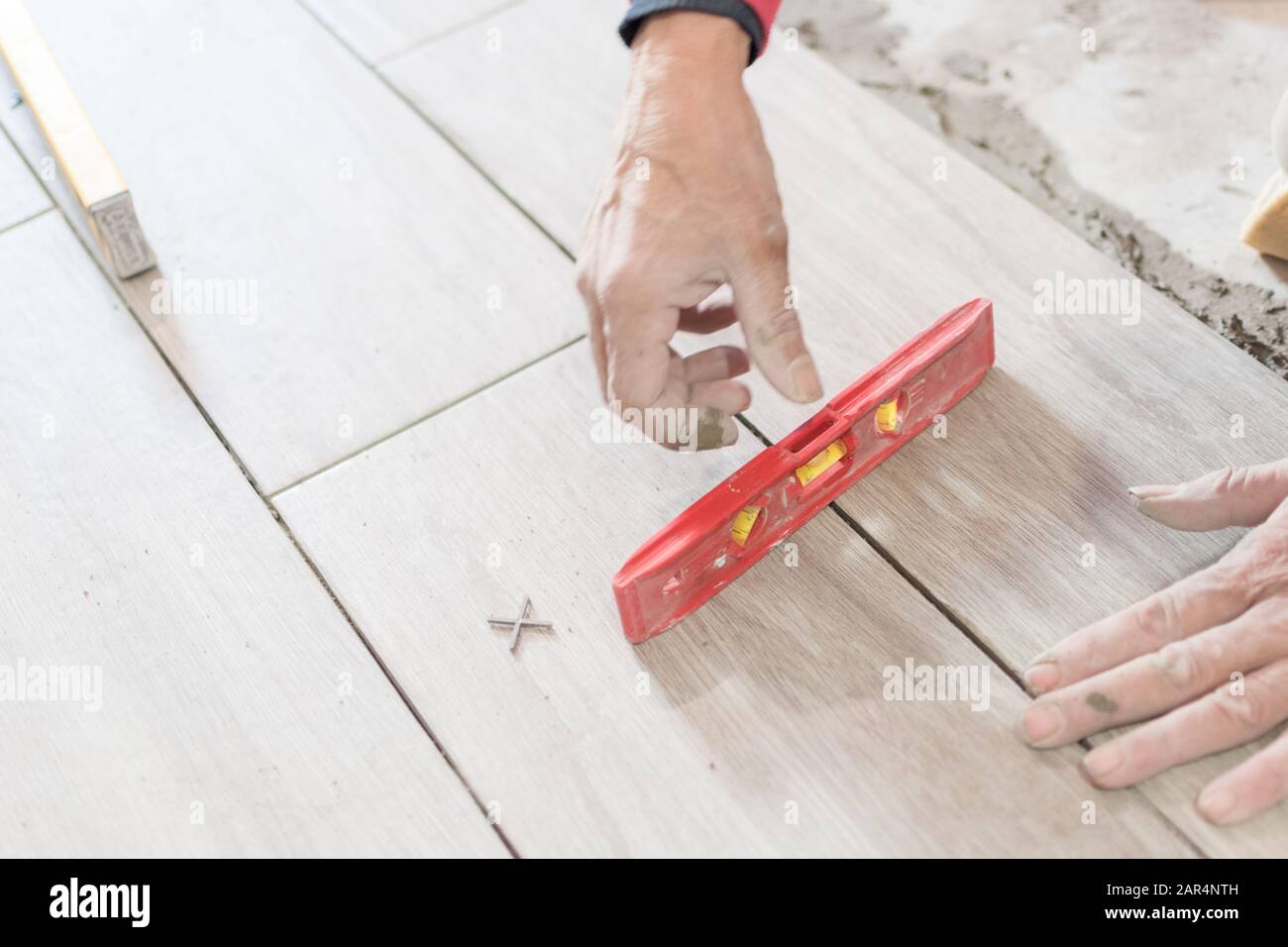 Man installing rectangular shaped floor tiles in kitchen. Applying ...