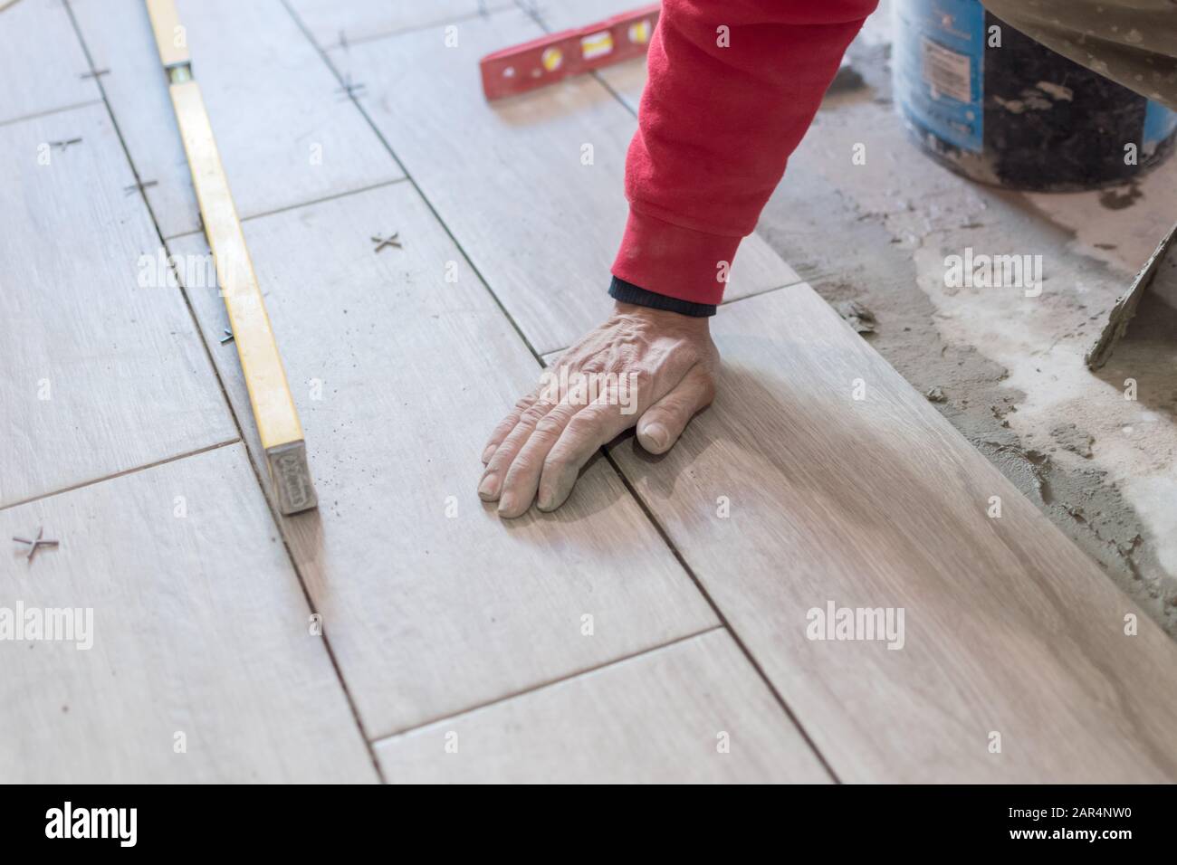 Man installing rectangular shaped floor tiles in kitchen. Applying ...