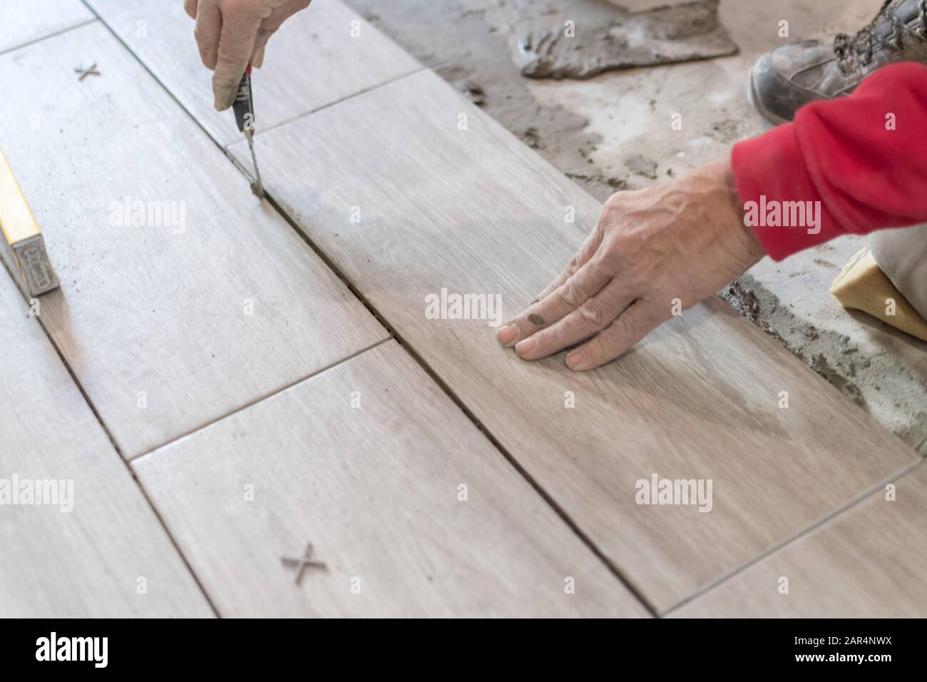 Man installing rectangular shaped floor tiles in kitchen. Applying ...