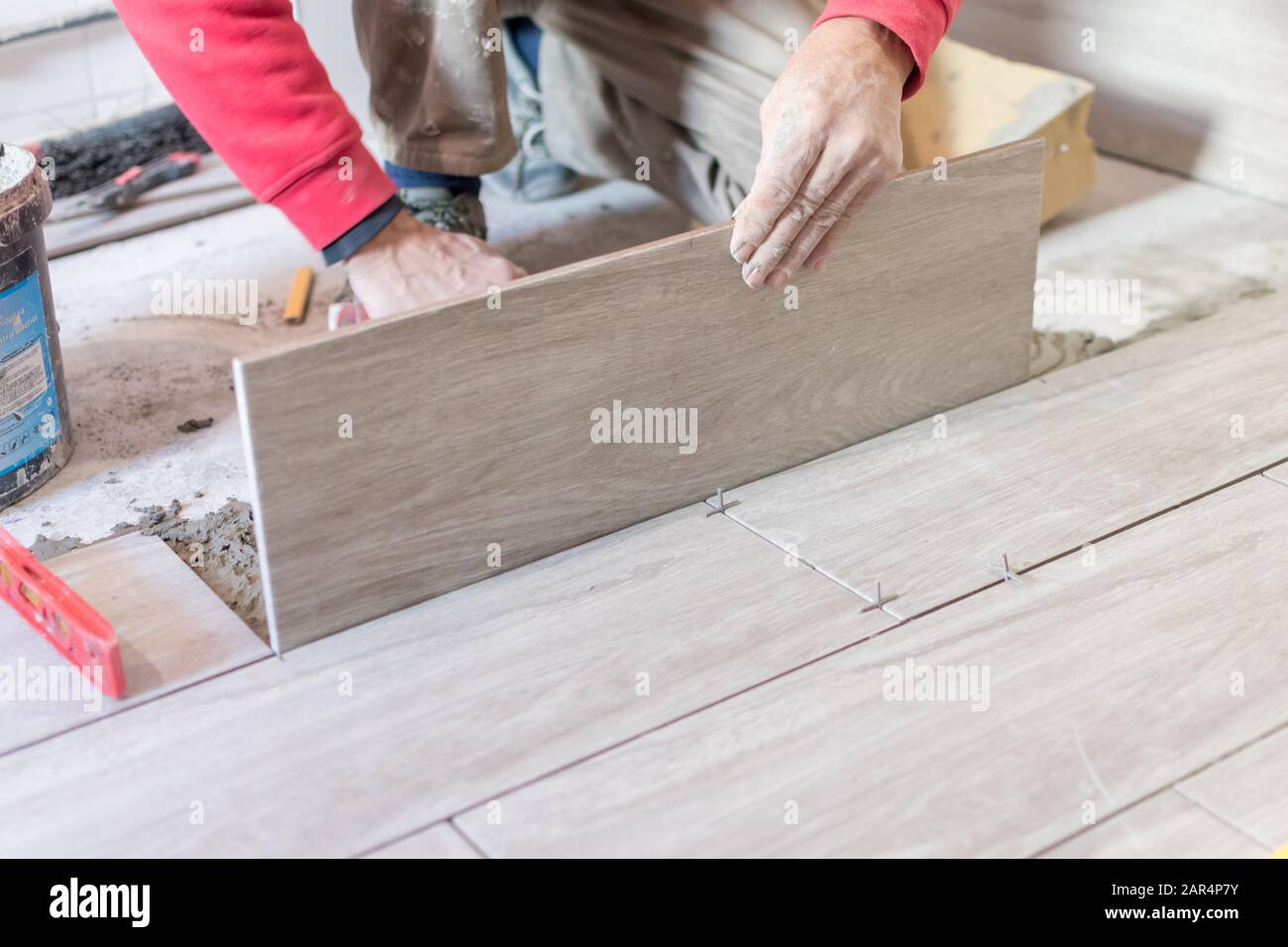 Man installing rectangular shaped floor tiles in kitchen. Applying ...