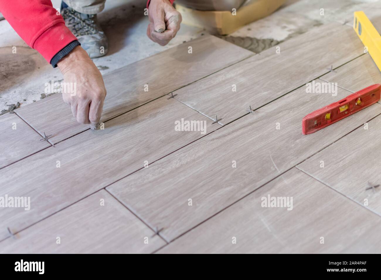 Man installing rectangular shaped floor tiles in kitchen. Applying ...
