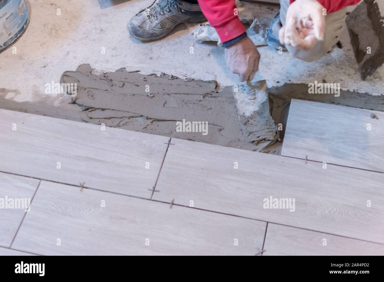 Man installing rectangular shaped floor tiles in kitchen. Applying ...