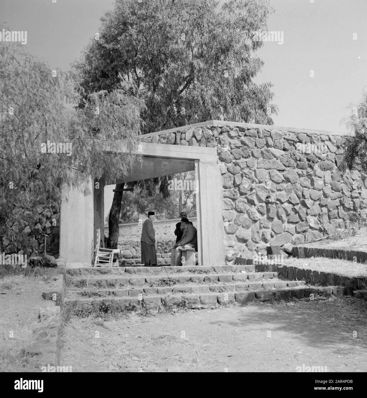 Some men in a triangular concrete pavilion on natural stone steps near ...