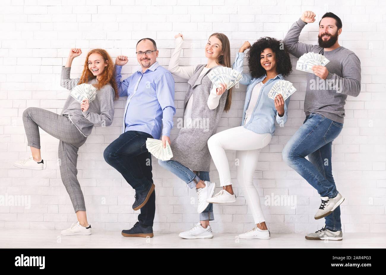Lucky people rejoicing success, posing with lot of dollar money cash ...