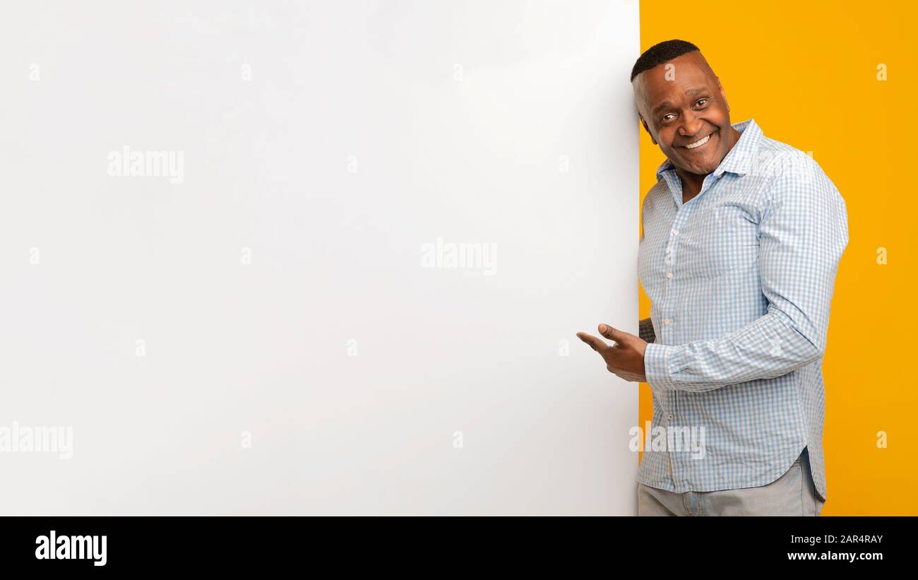 Positive mature man pointing at blank white placard Stock Photo - Alamy