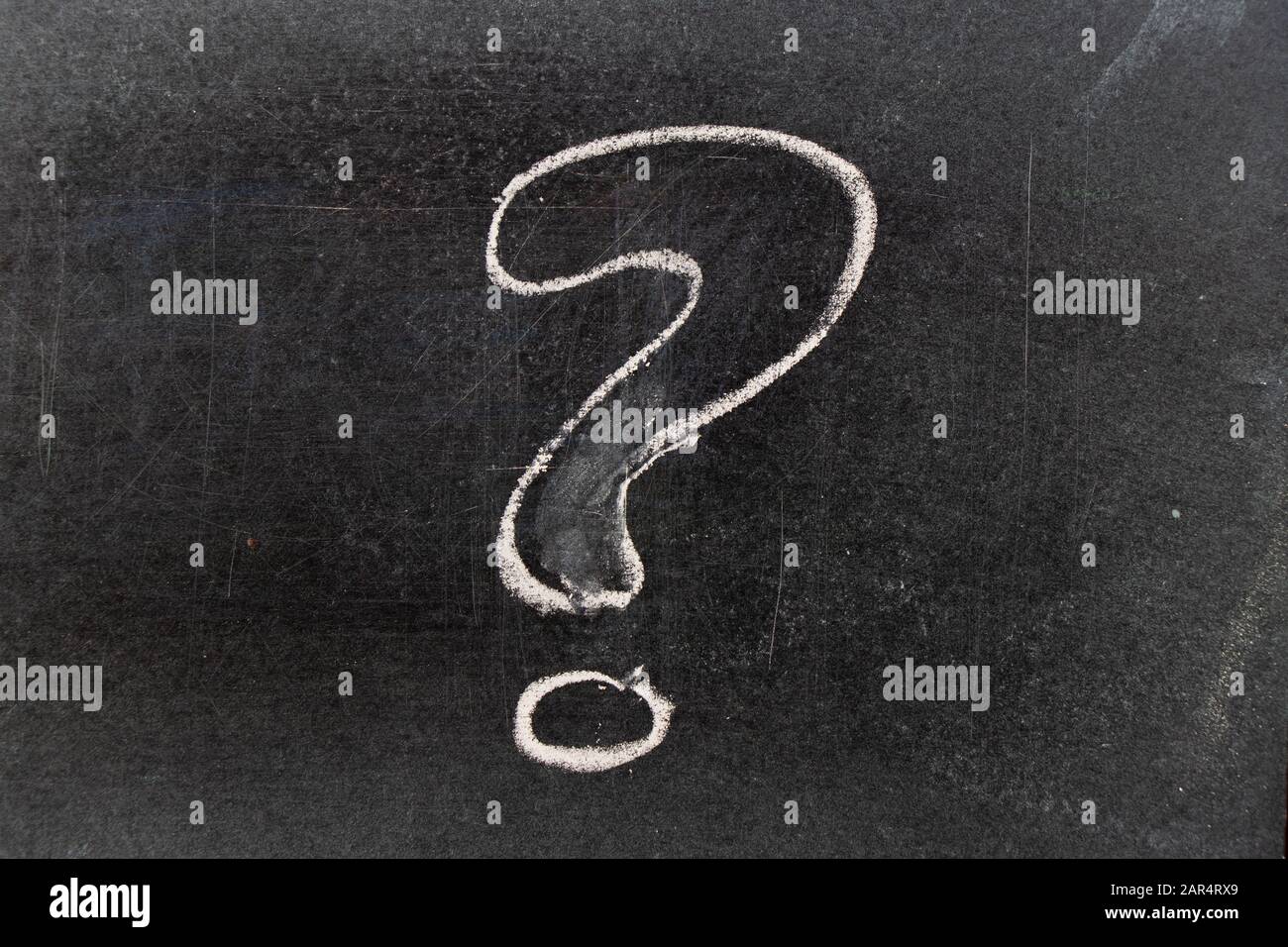 White color chalk hand drawing in question mark shape on blackboard ...