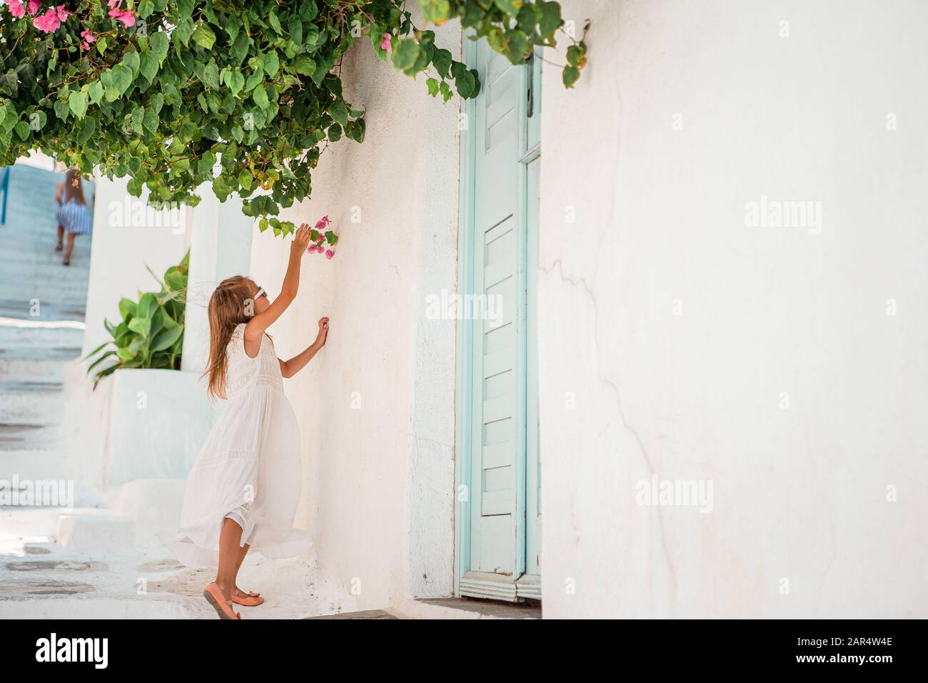 Adorable little girl at old street of typical greek traditional village ...